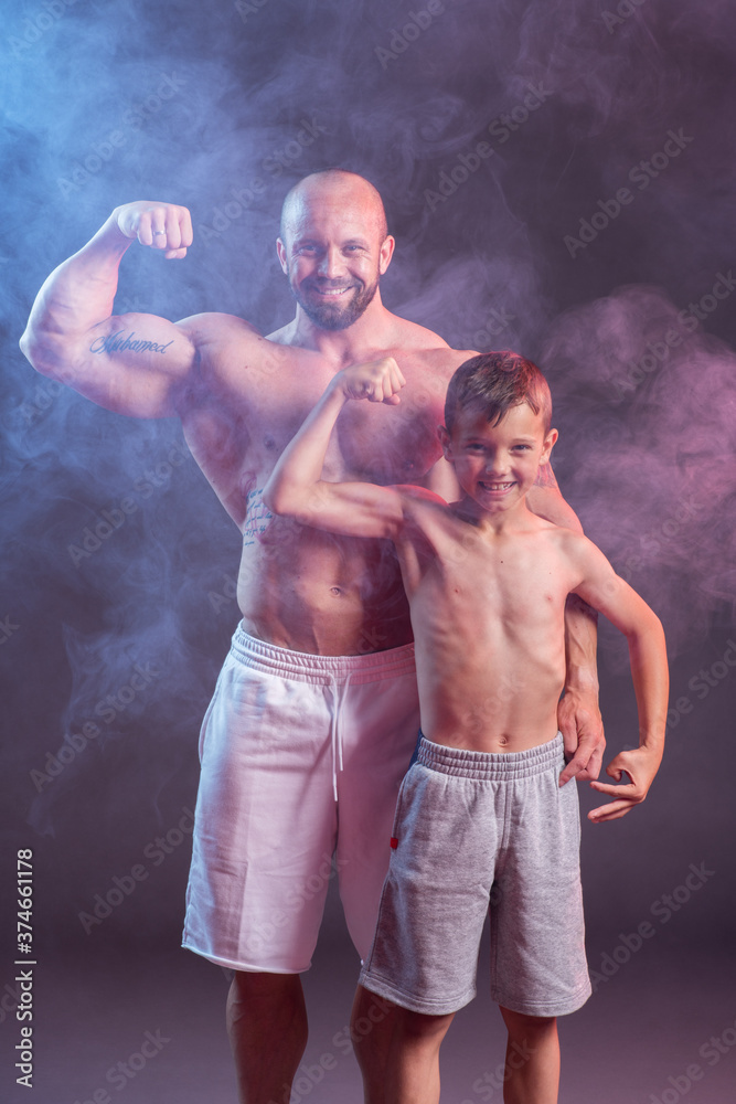 Powerful muscular man shirtless posing with his son in the studio with ...