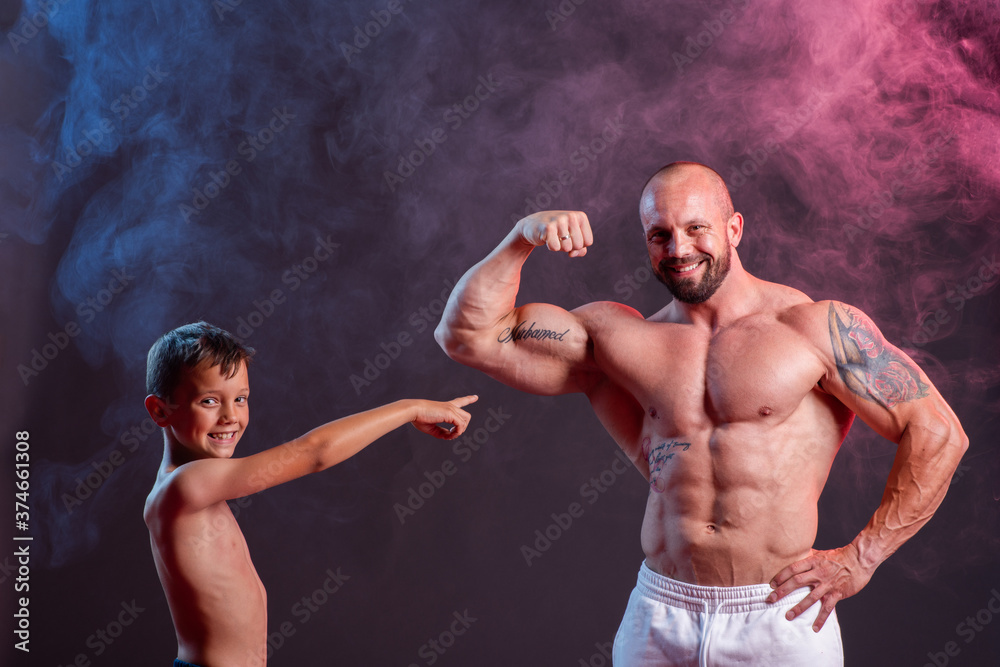 Powerful muscular man shirtless posing with his son in the studio with ...