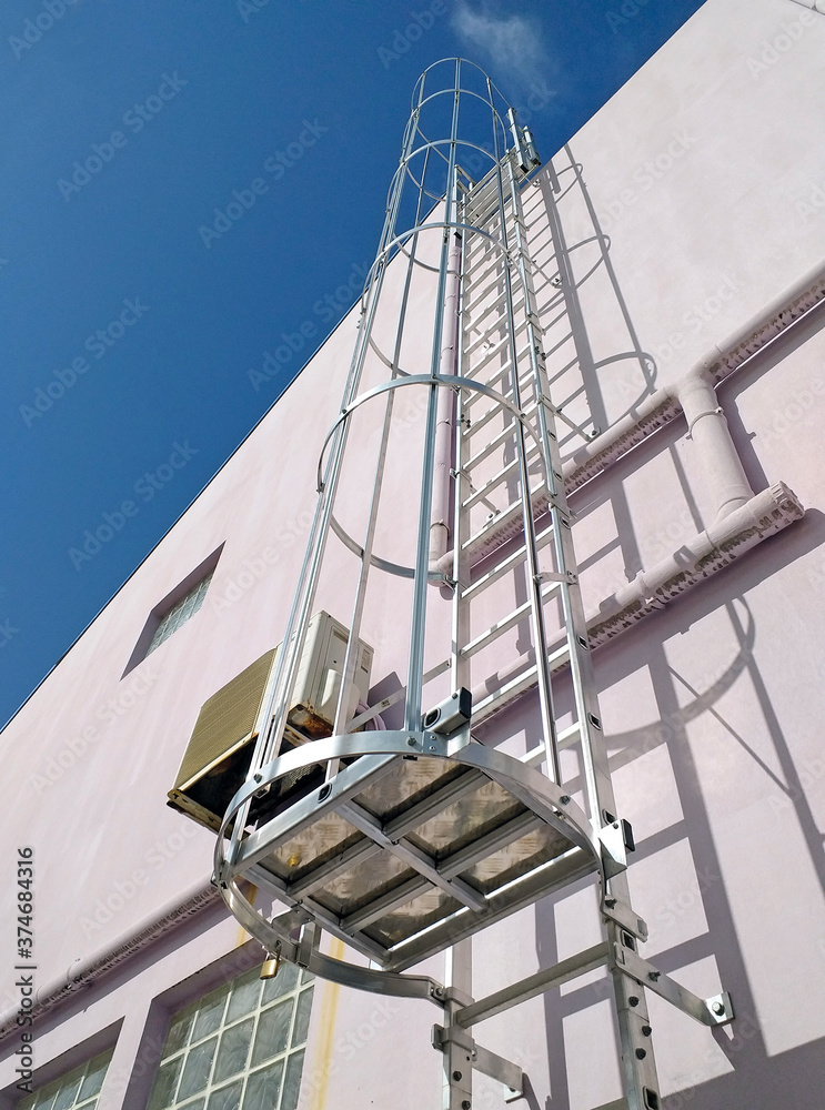 Low angle view of an exterior vertical fixed ladder with safety cage in ...