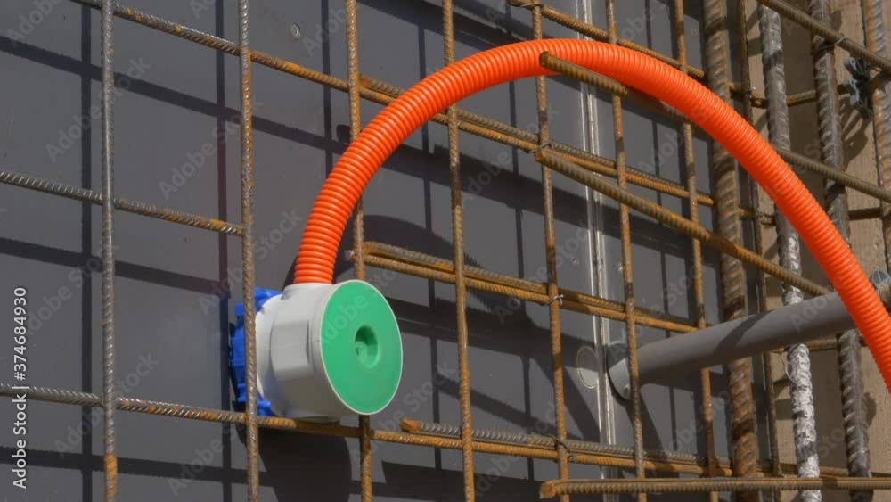 CLOSE UP: Thin corrugated orange conduit runs out of an electricity ...