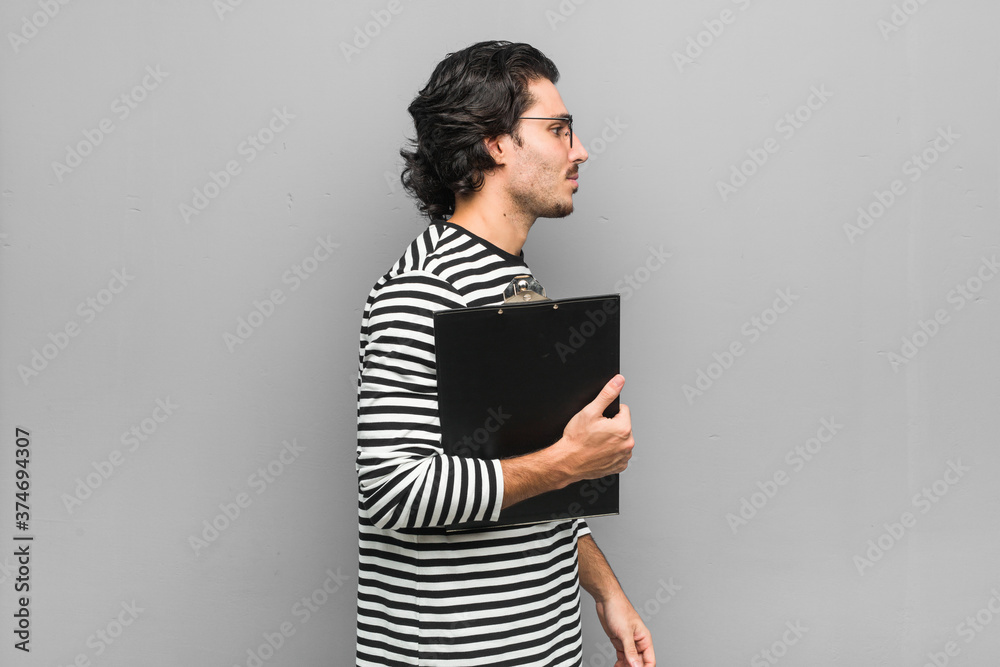 Young employee man holding an inventory gazing left, sideways pose ...