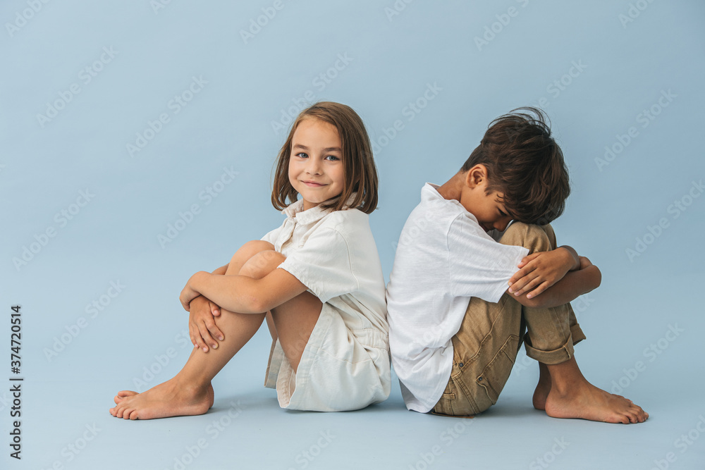 Couple of children of roughly the same age sitting on the floor back to ...