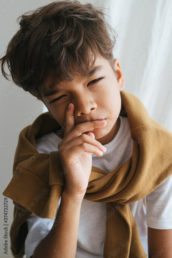 Squinting indian ten year old asian kid looking at camera, touching his ...