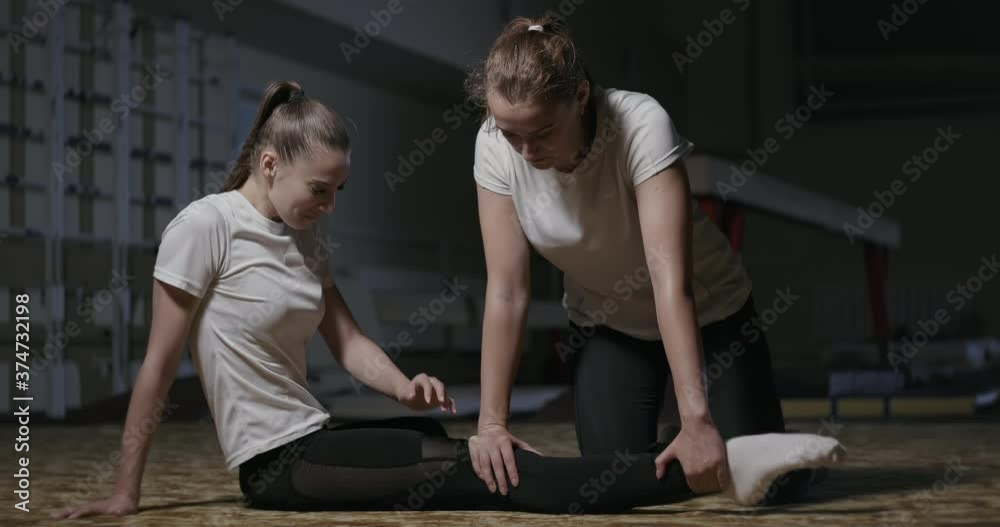 Gymnastics coach, two gymnasts. One gymnast stretches the other ...
