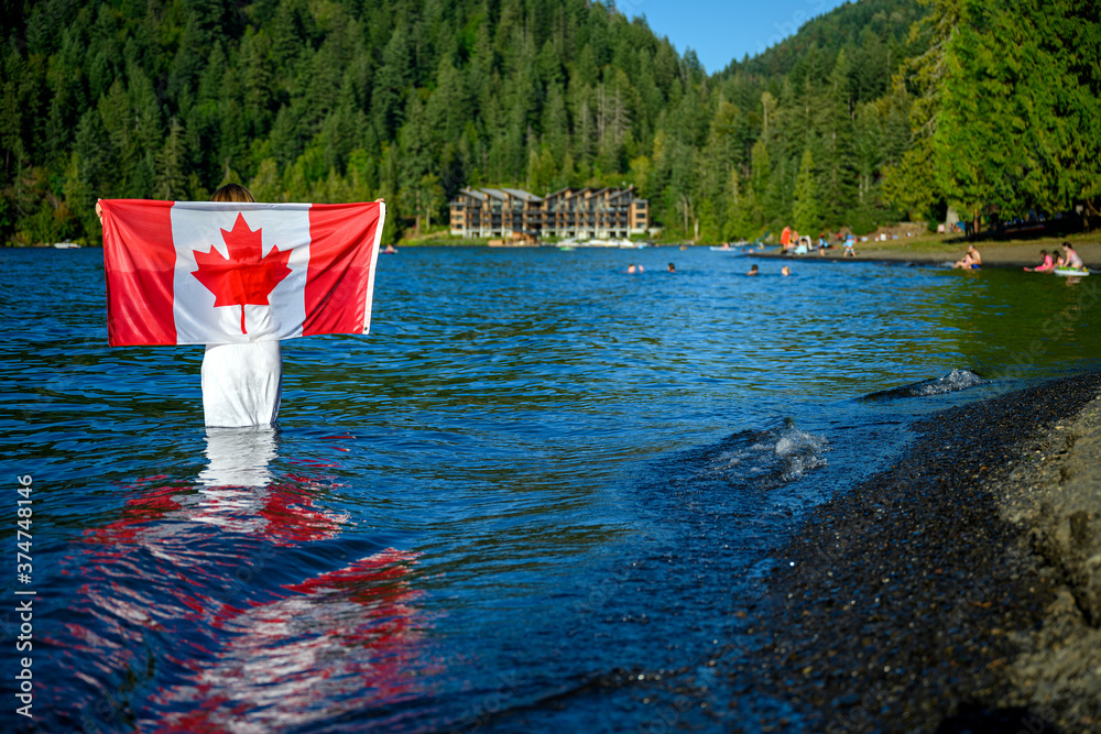 Patriot woman standing in the mazarine color water of the Cultus Lake ...