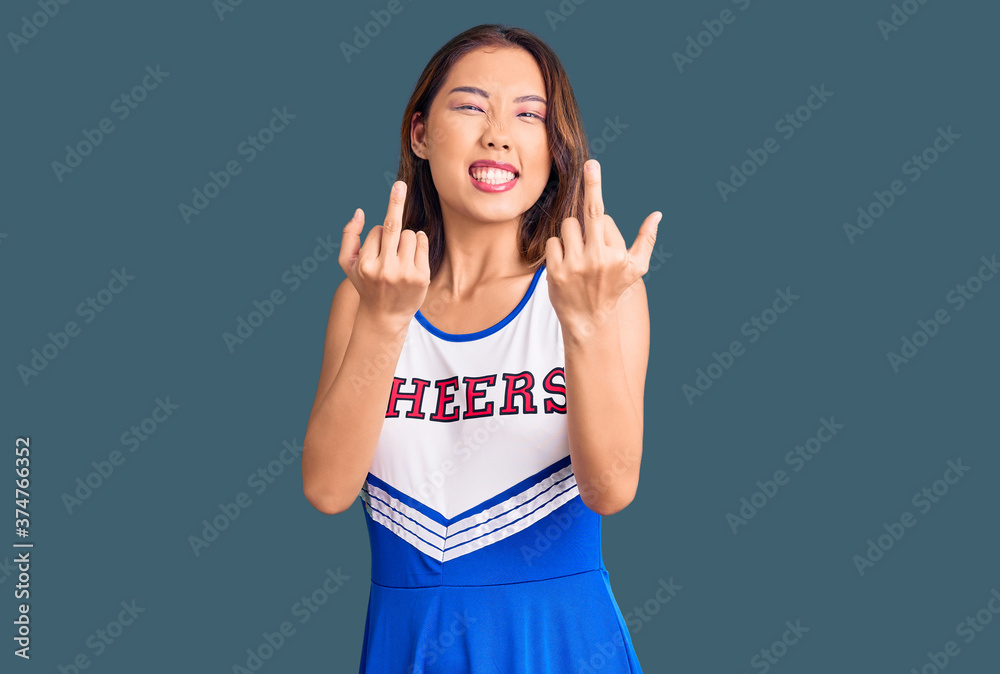 Young beautiful chinese girl wearing cheerleader uniform showing middle ...