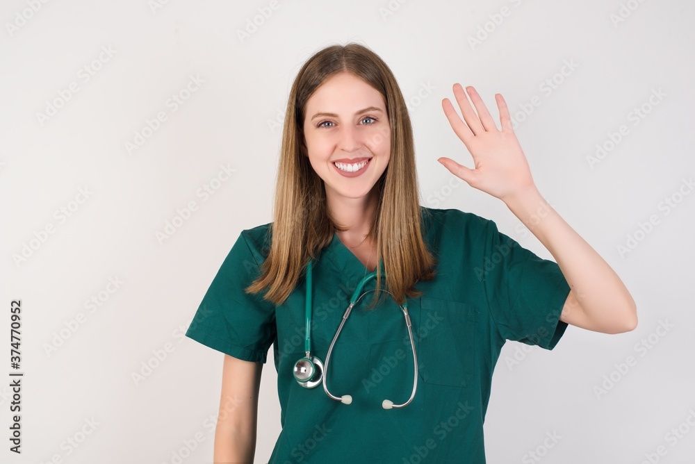 Female doctor wearing a green scrubs and stethoscope Waiving saying ...