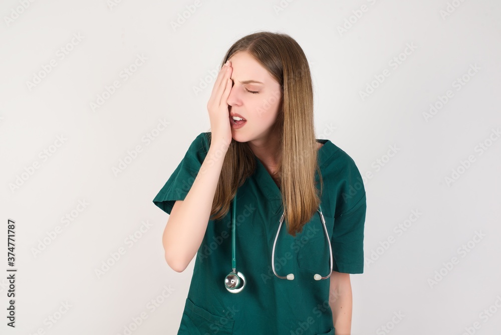 Female doctor wearing a green scrubs and stethoscope background Yawning ...