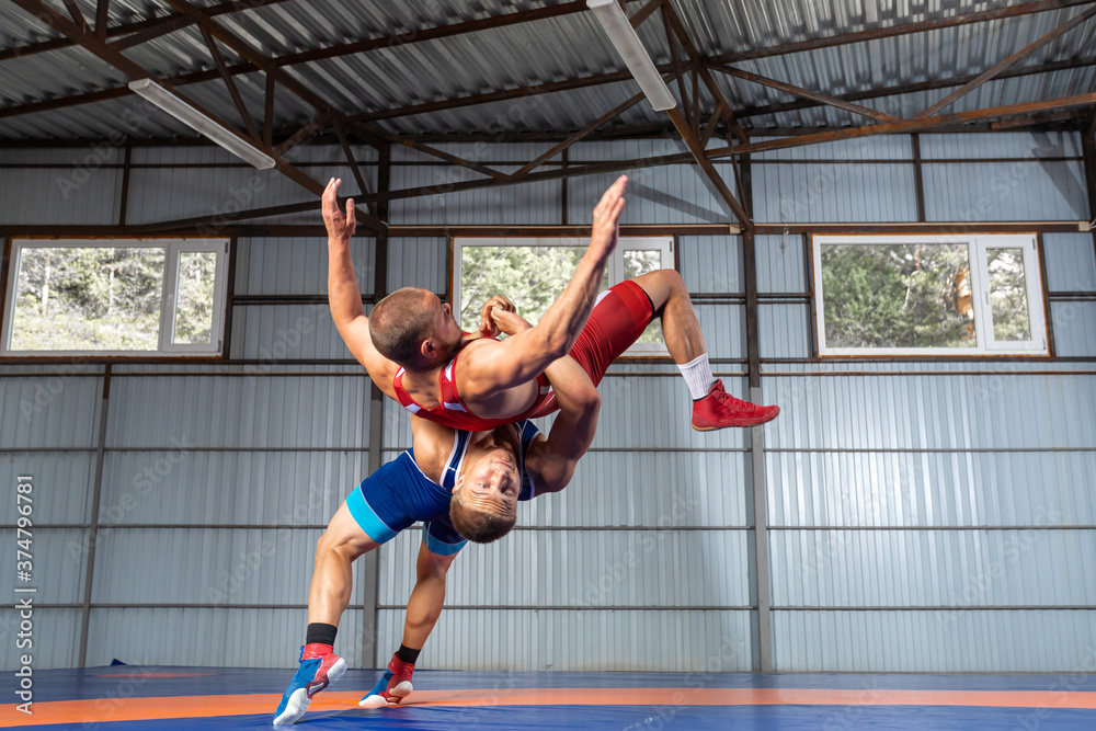 Two young sportsmens wrestlers in red and blue uniform wrestling ...