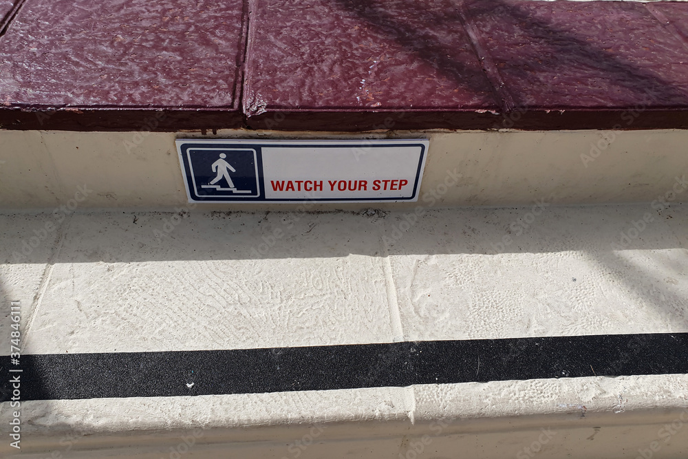 Plate with a reminding sign "Watch your step" and a black strip on the ...