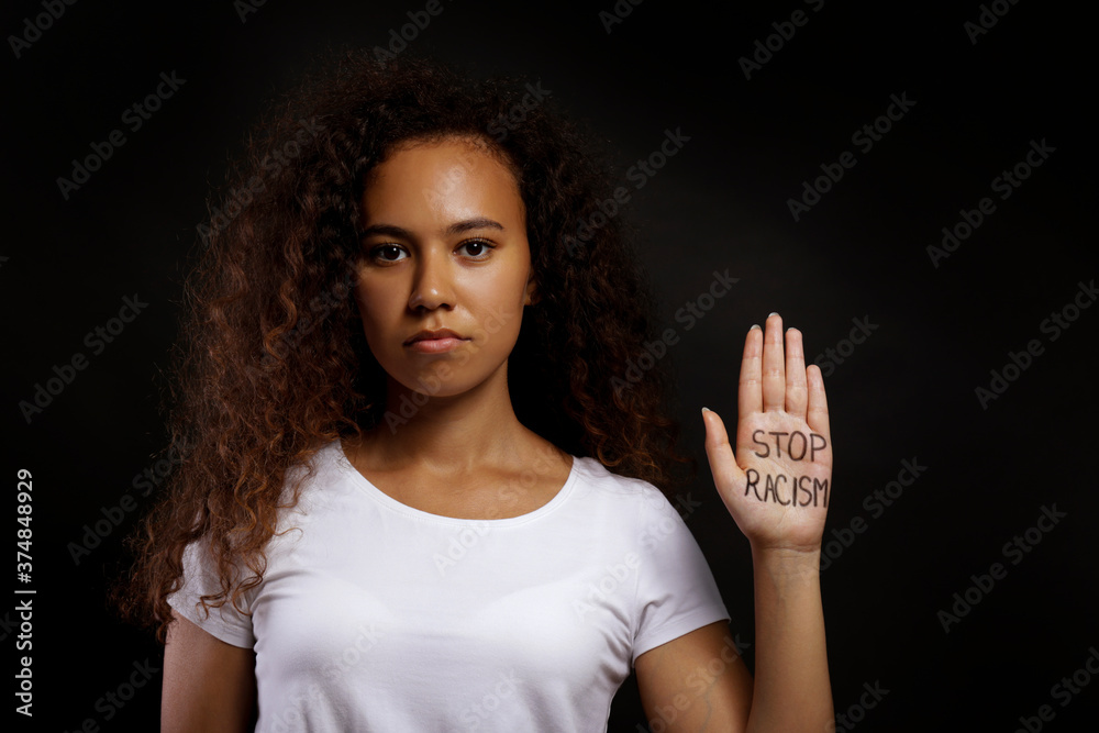 Portrait of young beautiful black woman showing a stop racism slogan ...
