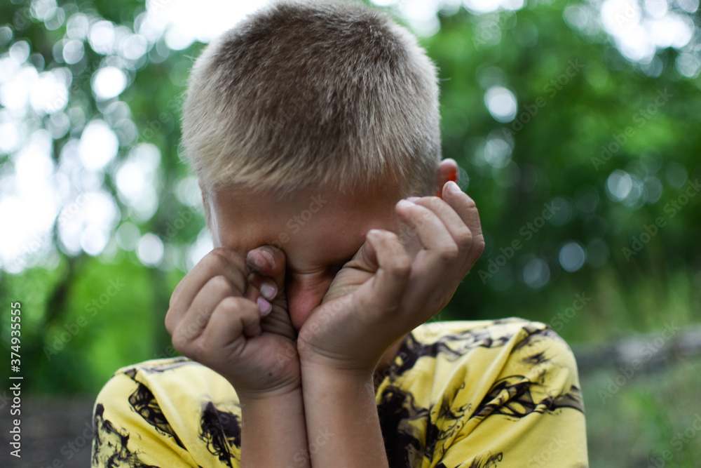 boy is crying outdoors. The teenager child is crying. Strong resentment ...