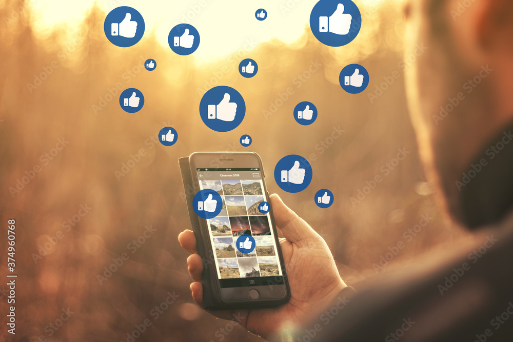 Young man watching Facebook on his smartphone during a walk in the ...