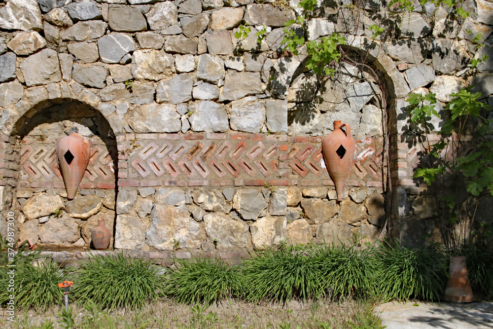 Old stone structure with urns built into a stone wall in the gardens of ...