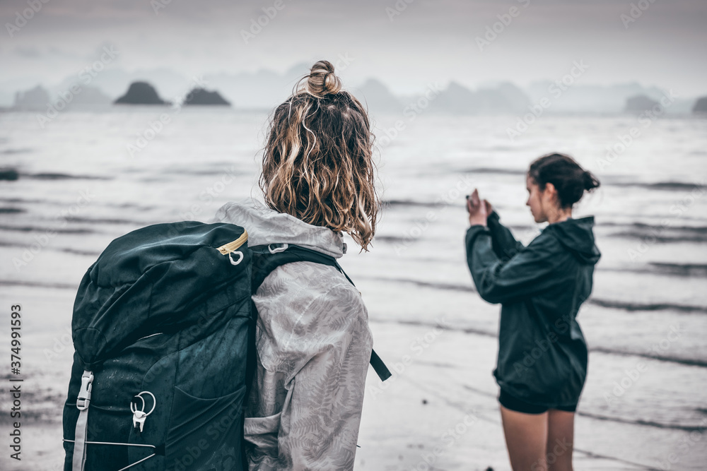 Two backpacker friends, just arrived, in the rain, on a Thai island ...