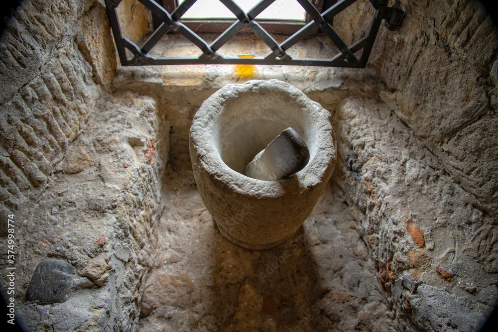 old antique stone kitchen mortar in the window of a medieval castle ...