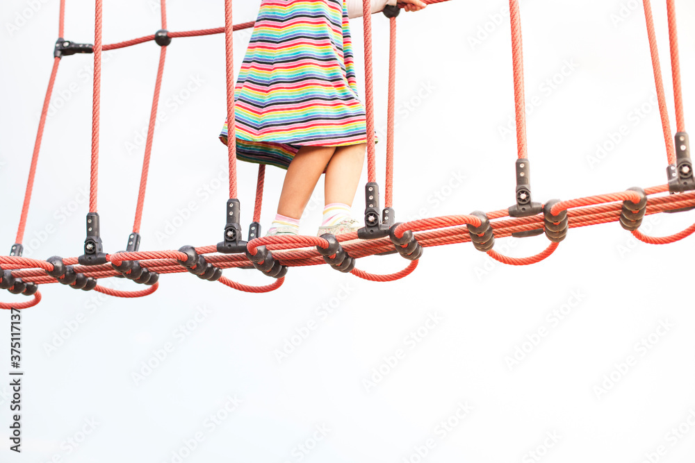 Child balances over rope bridge in climbing park. Kind balanciert über ...