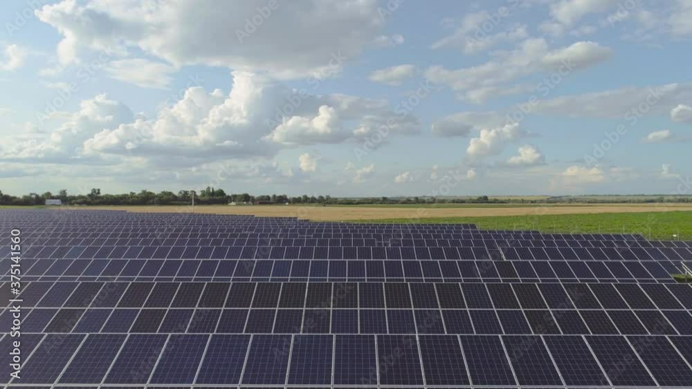 Flying over a field of solar panels, around green fields. Renewable ...