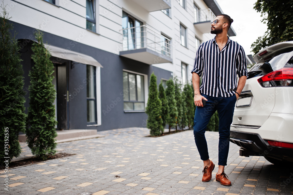Successful arab man wear in striped shirt and sunglasses pose near his ...