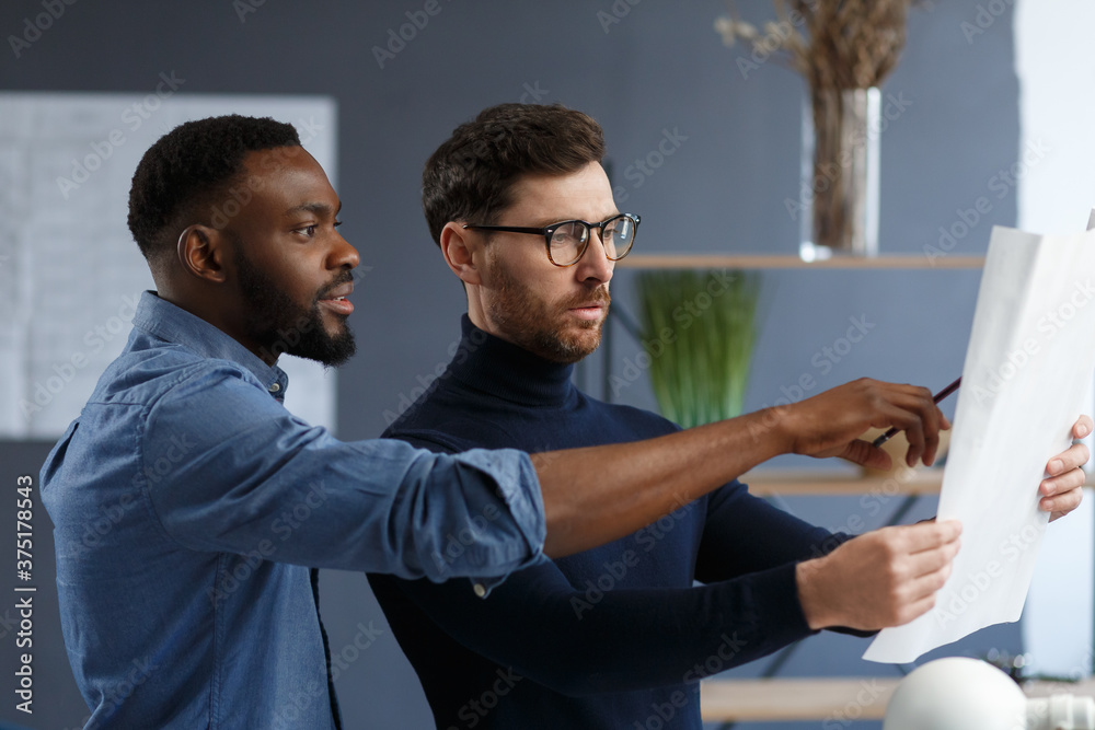 Multiracial engineer team working in office with blue prints and ...