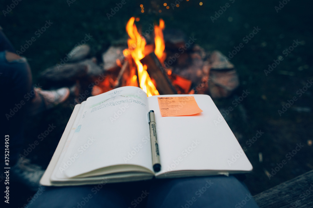 Campfire stories. Drawing and taking notes next to a campfire during ...