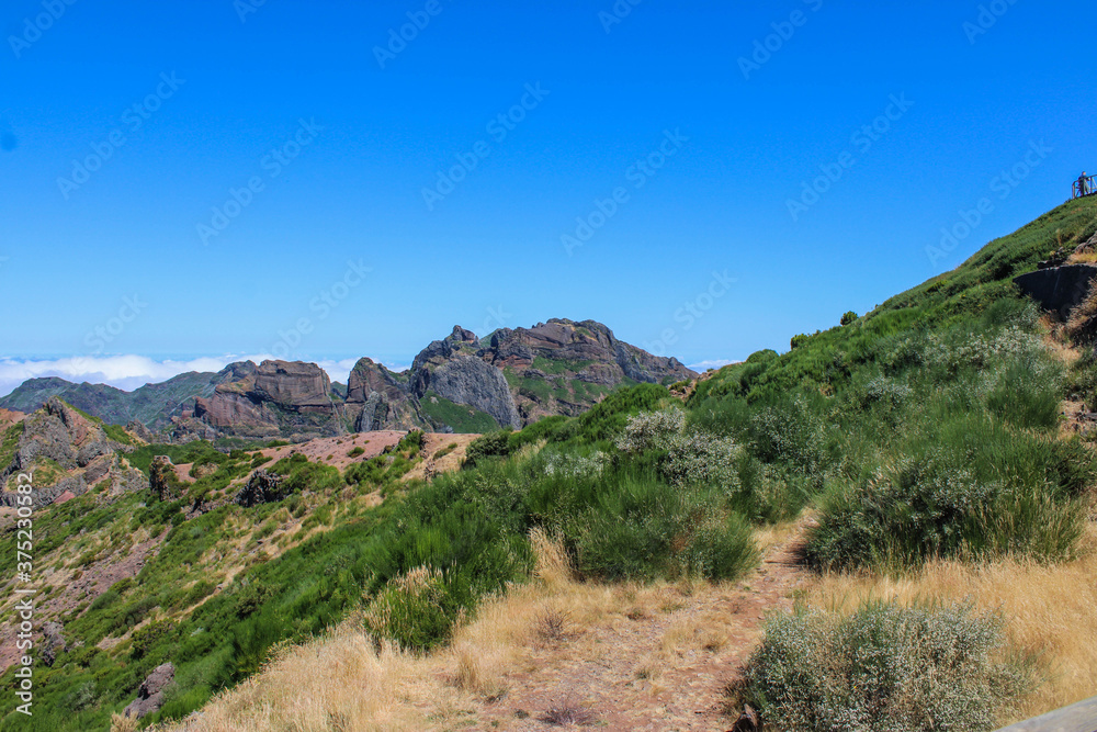 Grandes montañas de rocas con hojas secas y verdes entre nubes blancas ...