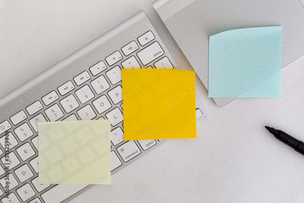Computer keyboard and a trackpad with three blank post it notes and a ...