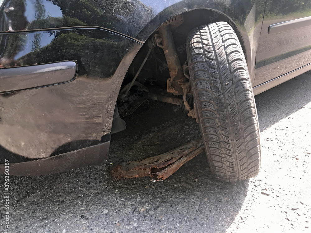 Damaged wheel of a car caused by hole in a rural road. A torn off wheel ...