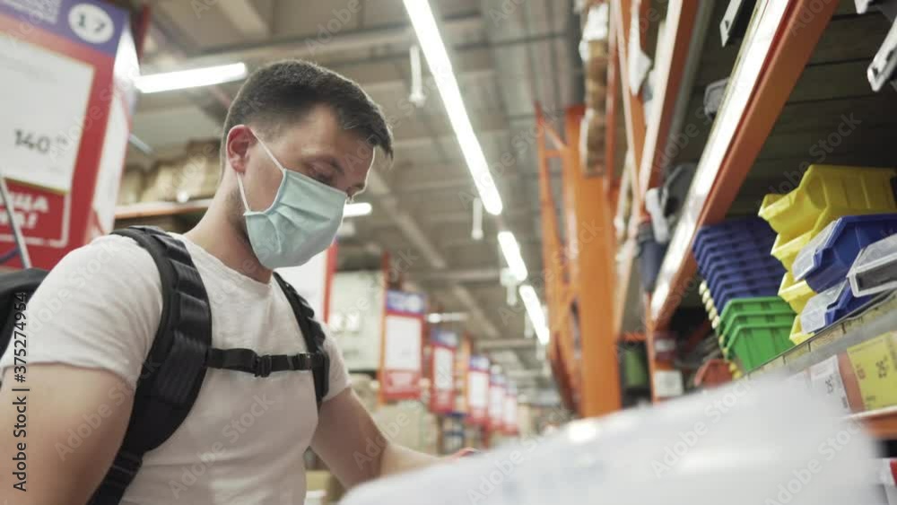 Customers with face masks due to coronavirus pandemic, in building supermarket selects a toolbox ...