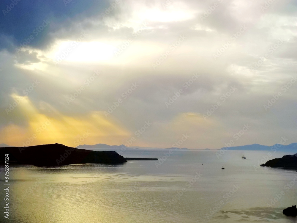 Natural Crepuscular rays above Nea Kameni island in Fira in Santorini ...