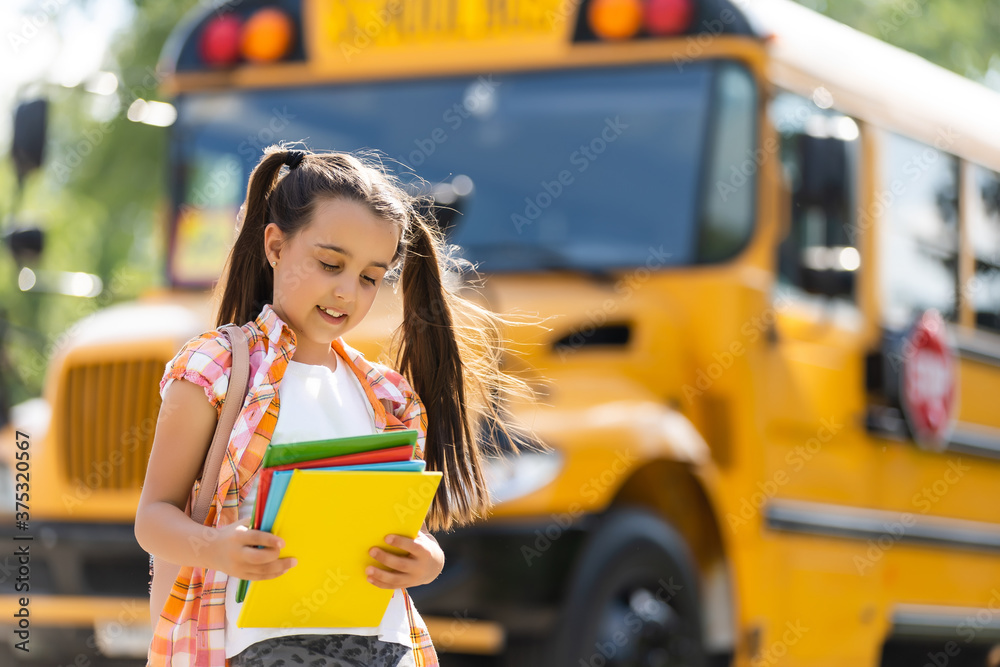 Little girl standing by a big school bus door with her backpack. Stock ...