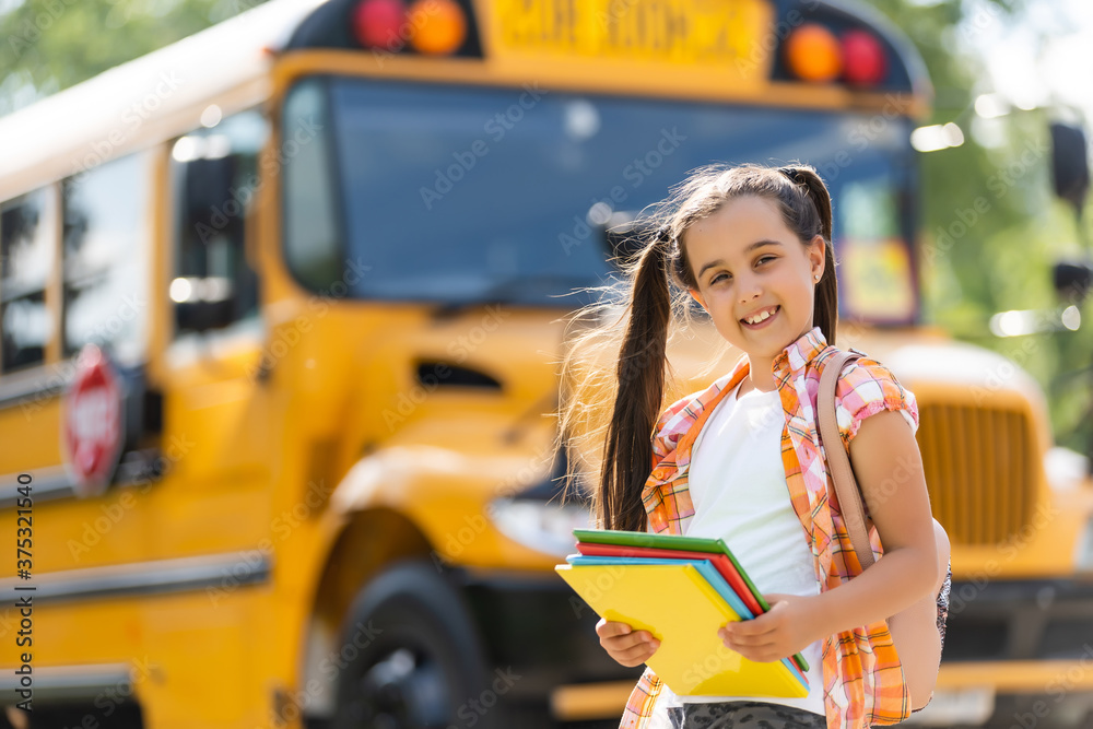Little girl standing by a big school bus door with her backpack. Stock ...
