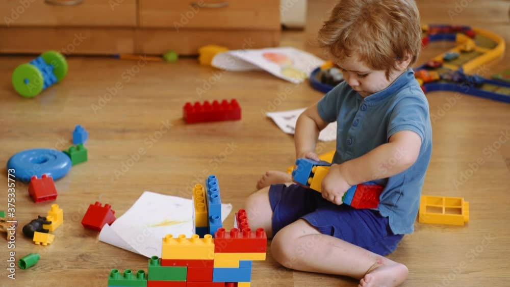 Funny curly baby boy with educational toy blocks. Children play at day ...