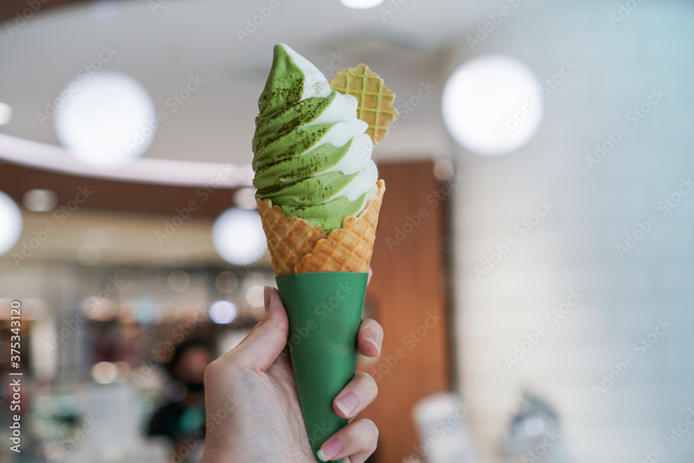 Matcha two tone soft serve ice cream. Woman holding a cone of matcha ...