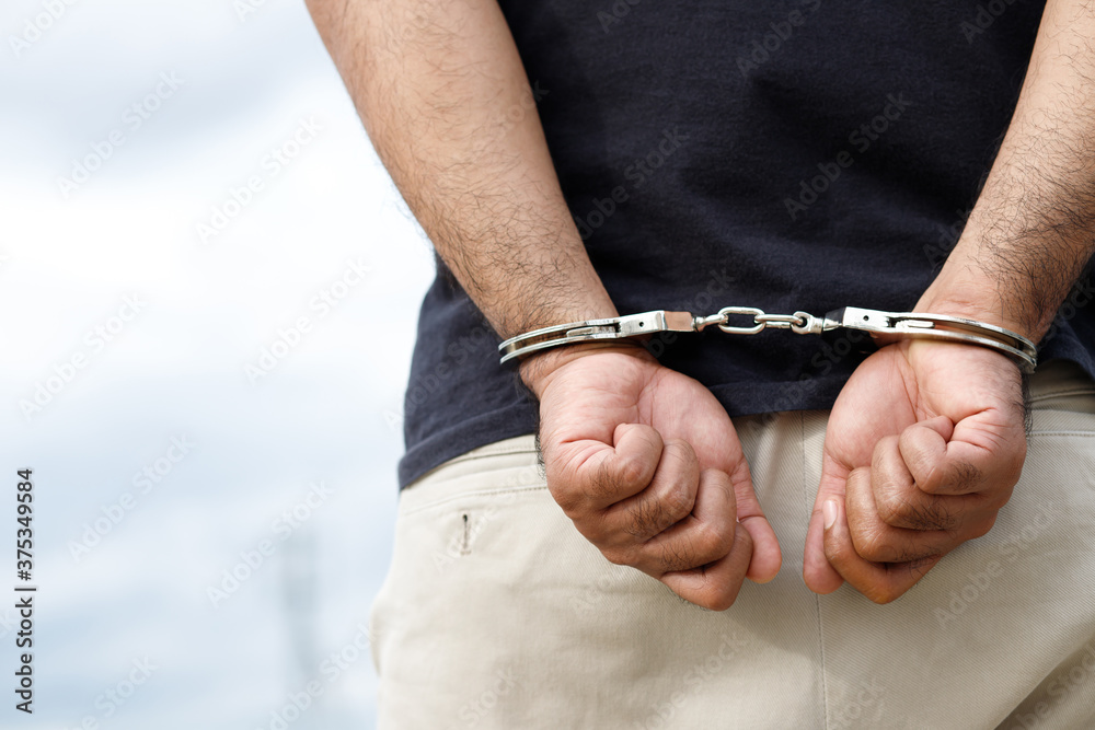 Arrest the offender. Prison male criminal standing in handcuffs with ...
