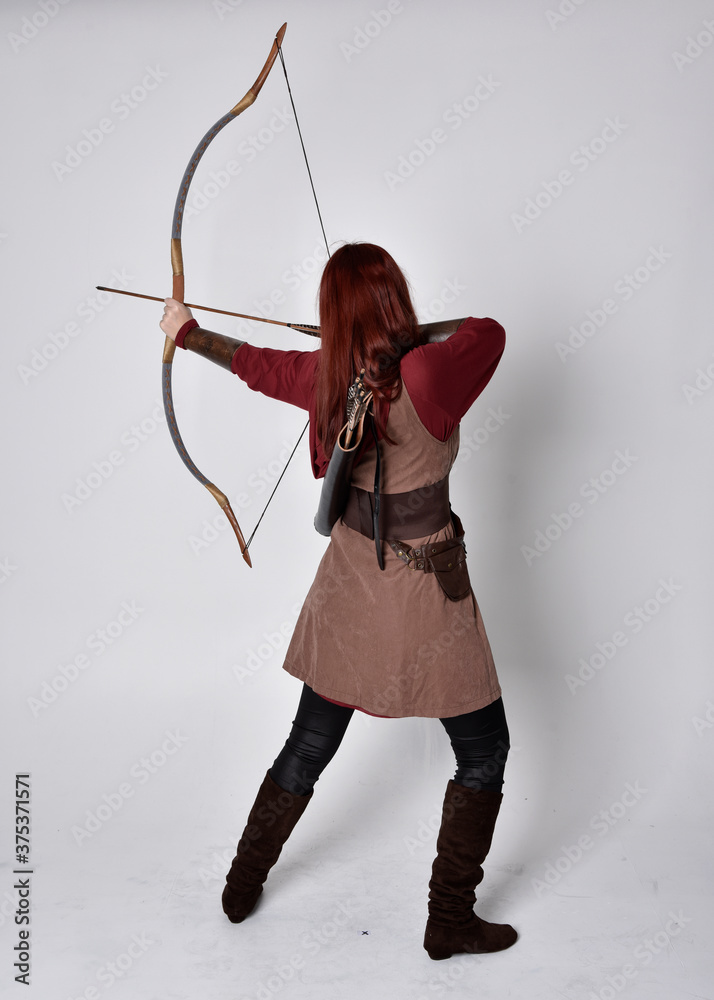 Full length portrait of girl with red hair wearing brown medieval ...