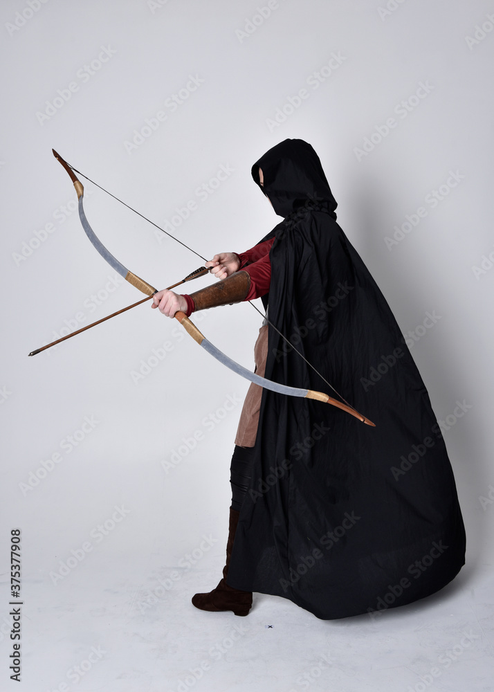 Full length portrait of girl with red hair wearing medieval archer ...