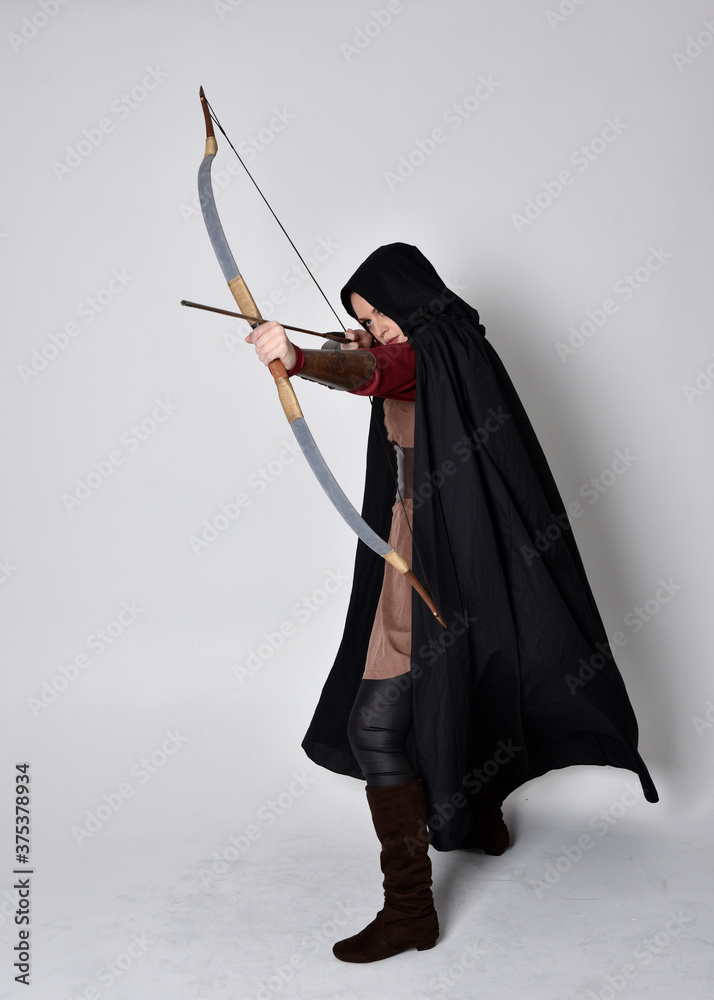 Full length portrait of girl with red hair wearing medieval archer ...