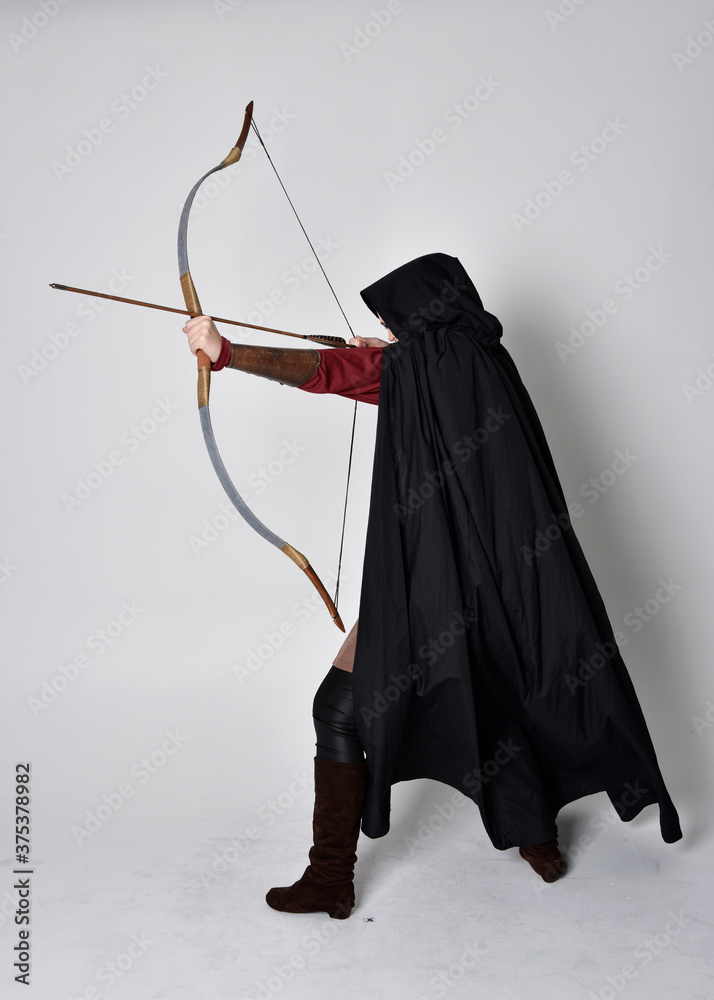 Full length portrait of girl with red hair wearing medieval archer ...