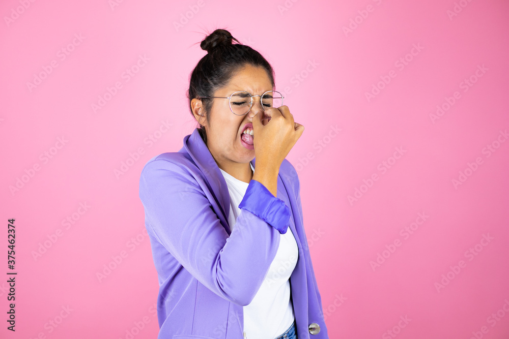 Young beautiful business woman over isolated pink background smelling ...