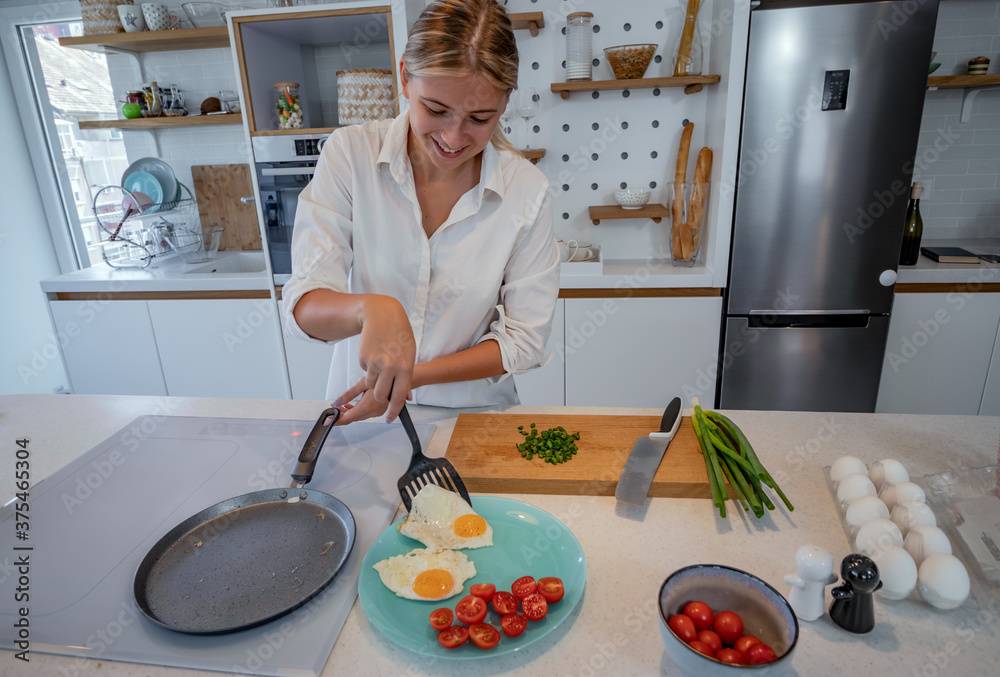 Beautiful young woman cooking in a modern equipped kitchen. Preparing ...