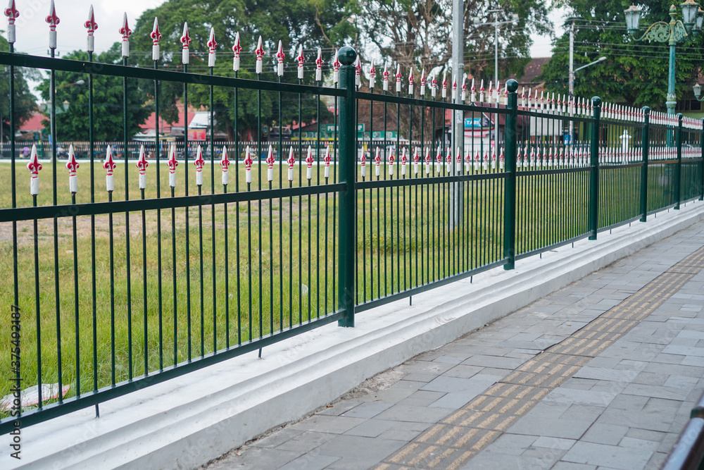 Pedestrian paths and green fences barrier in Alun-alun Utara area of ...