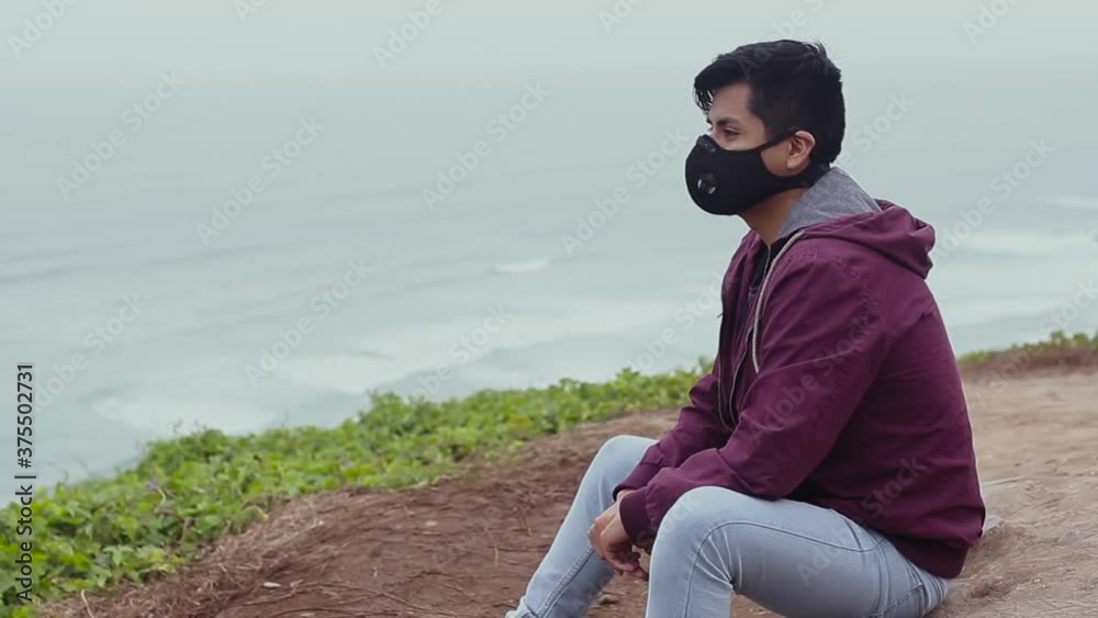 Un joven descansa con mascarilla por el parque frente al mar durante la ...