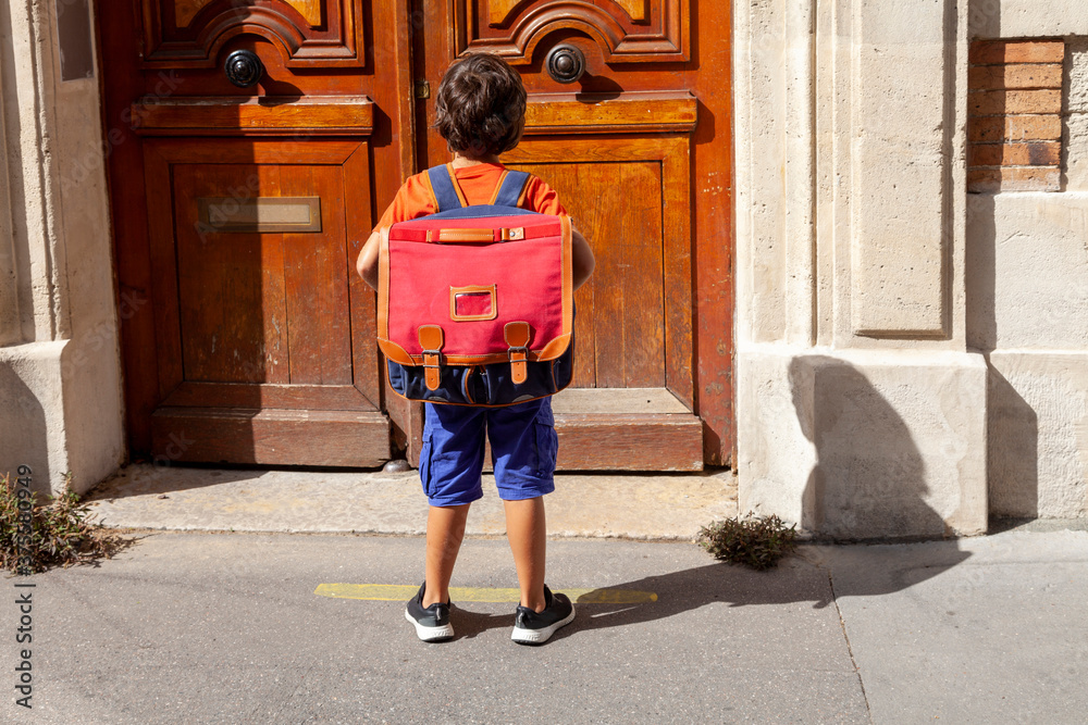 jeune écolier devant l'école avec son cartable sur le dos pour la ...
