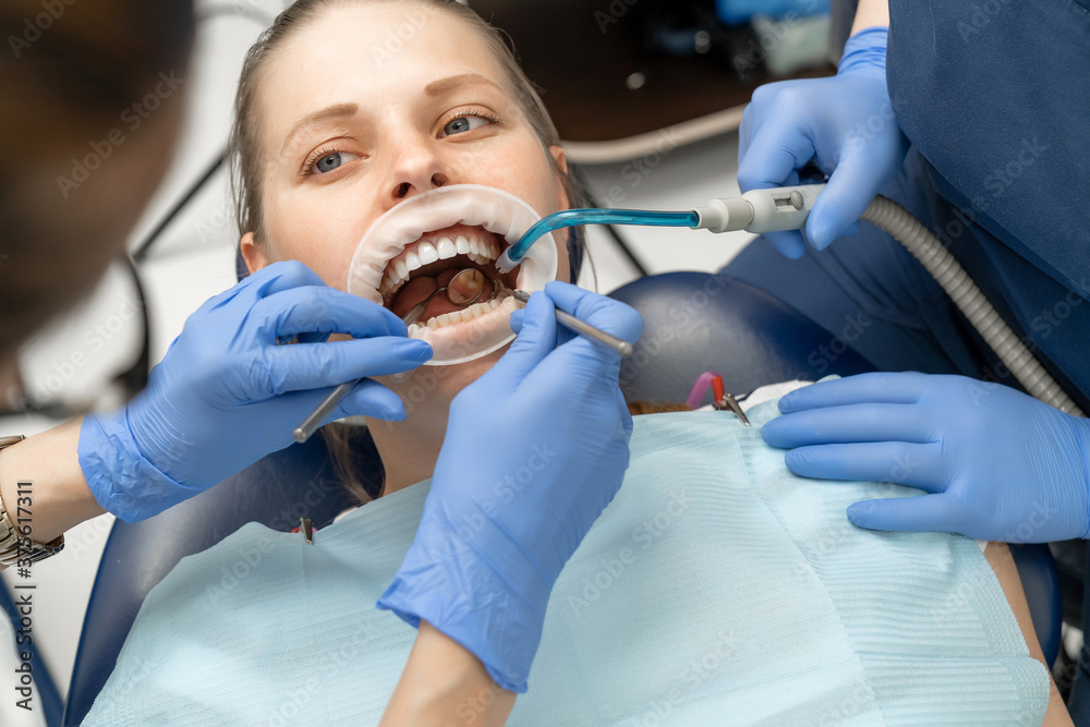 Doctor dentist examines the patient's mouth and teeth using a mirror ...