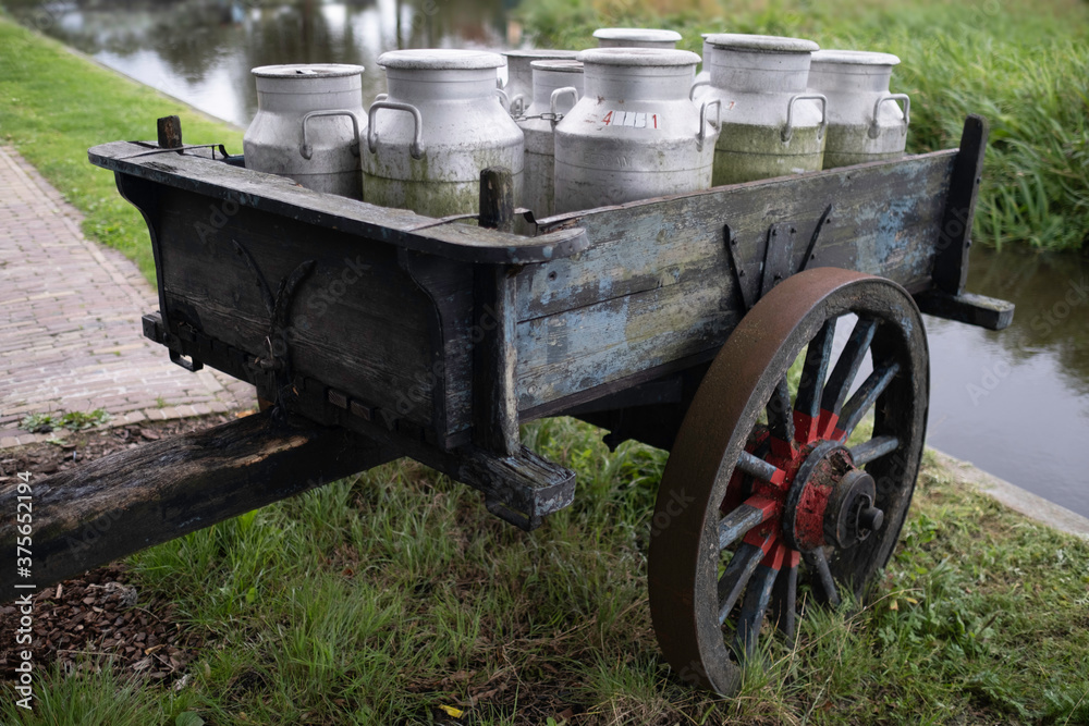 Milk cans on an old farmer's wheel cart in a garden in the Zaanse ...