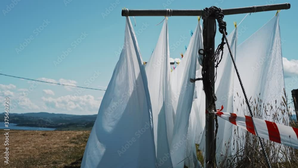white bed sheets on a clothes line moving gently with the wind in a ...