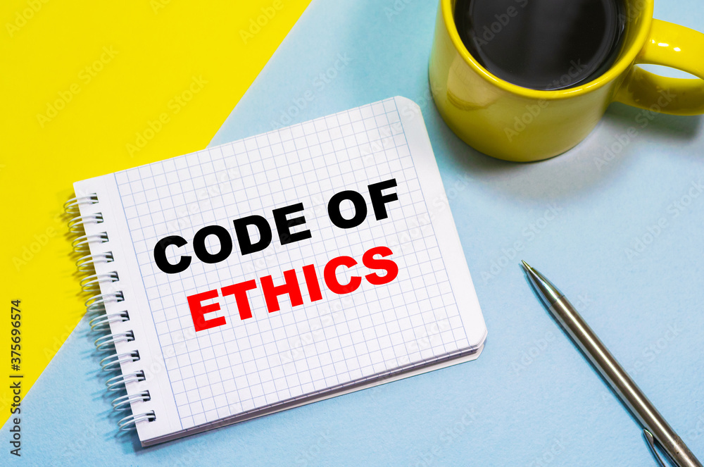 CODE OF ETHICS on a notepad on a blue-yellow background, a cup of ...