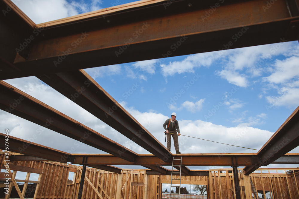 Carpenter man measures board up on steel beams Stock Photo | Adobe Stock