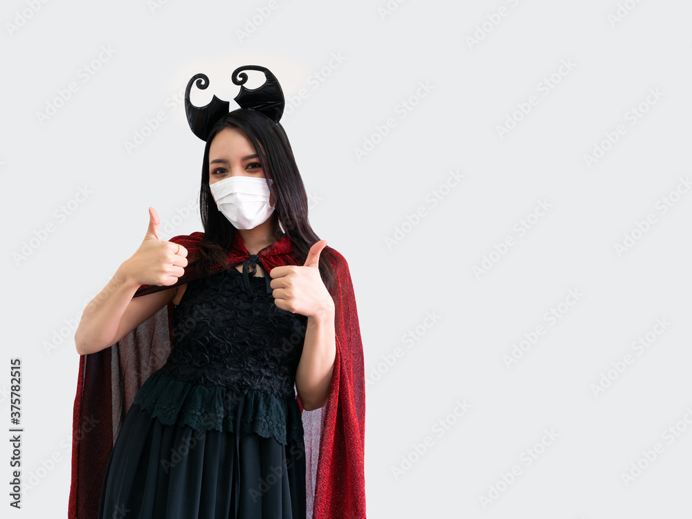 Asian pretty young girl show thumbs up two hand gesture about good Covid 19 prevention while ...